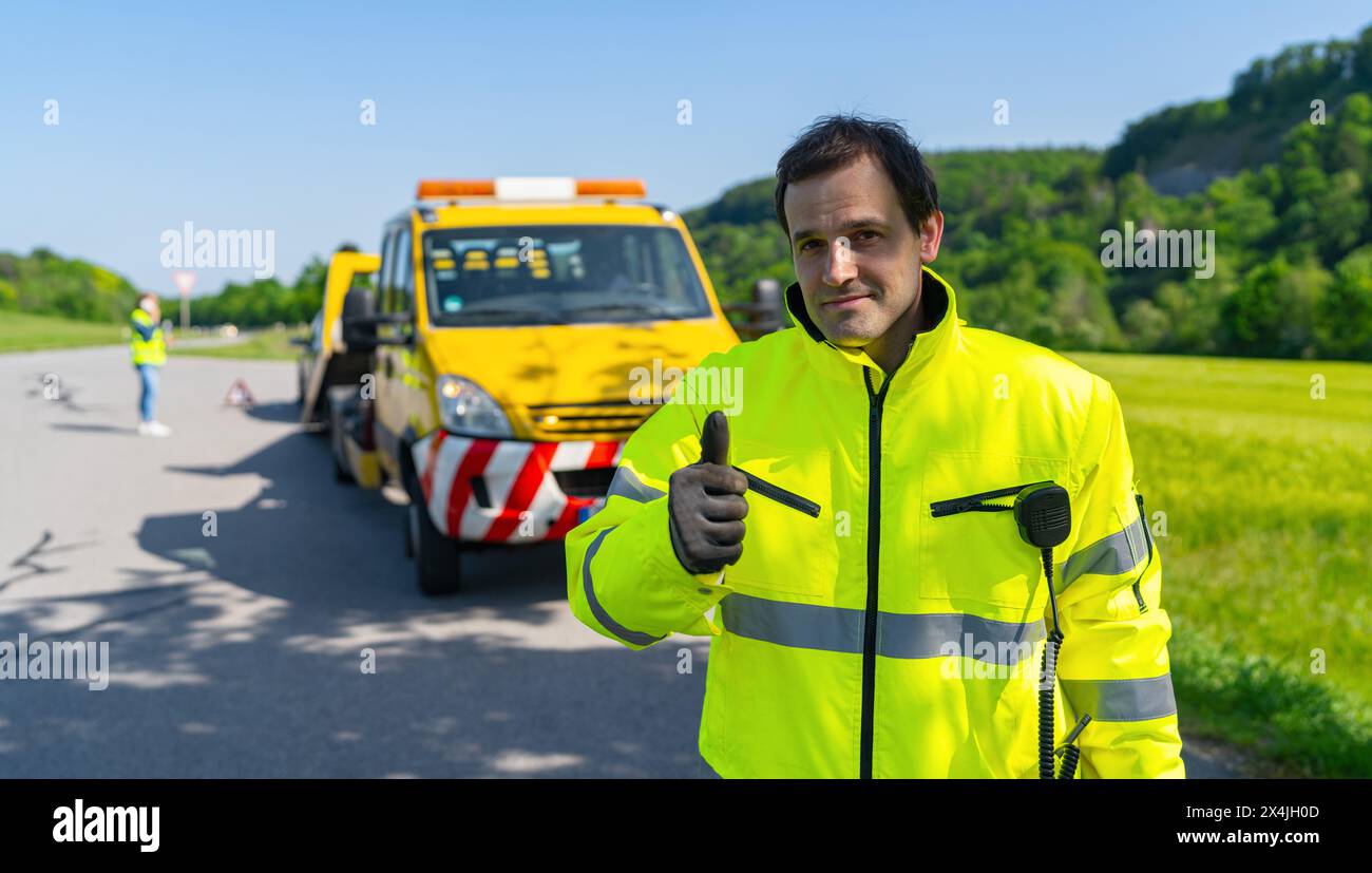 Tow truck operator with walkie-talkie giving thumbs up with a tow truck ...