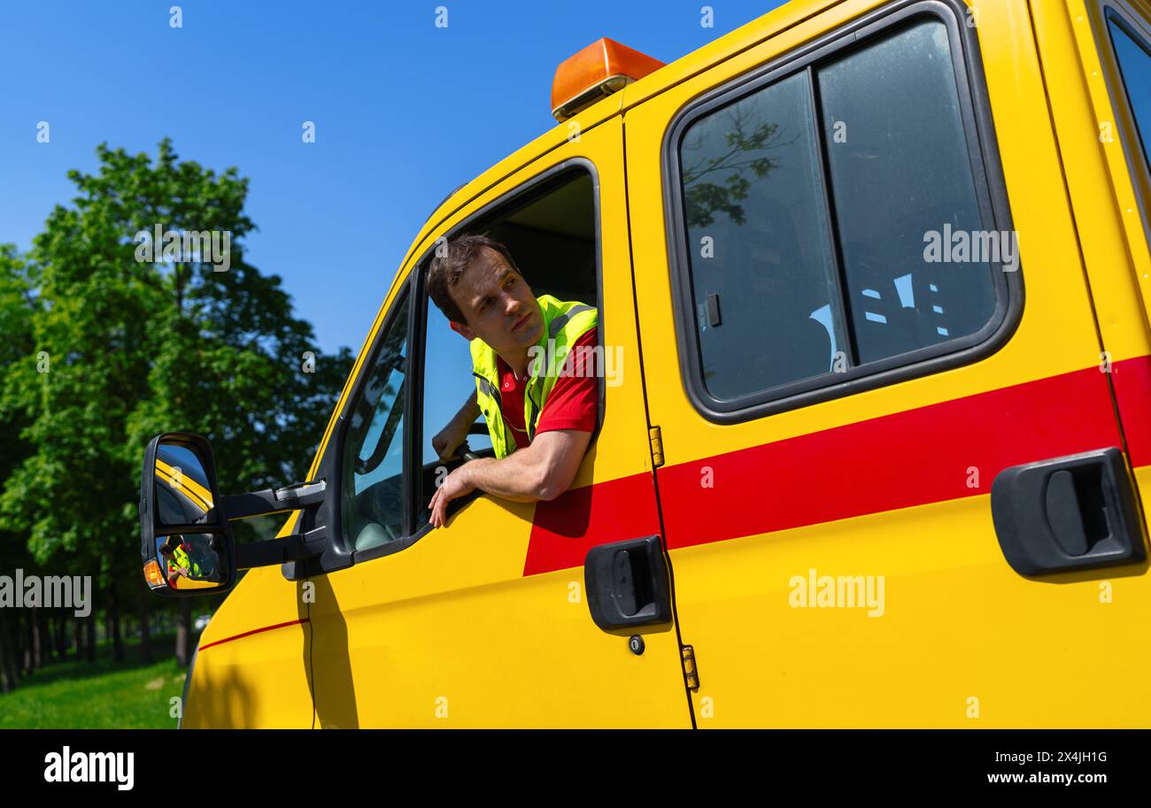 Tow truck driver sitting in a yellow truck looking out of the window ...