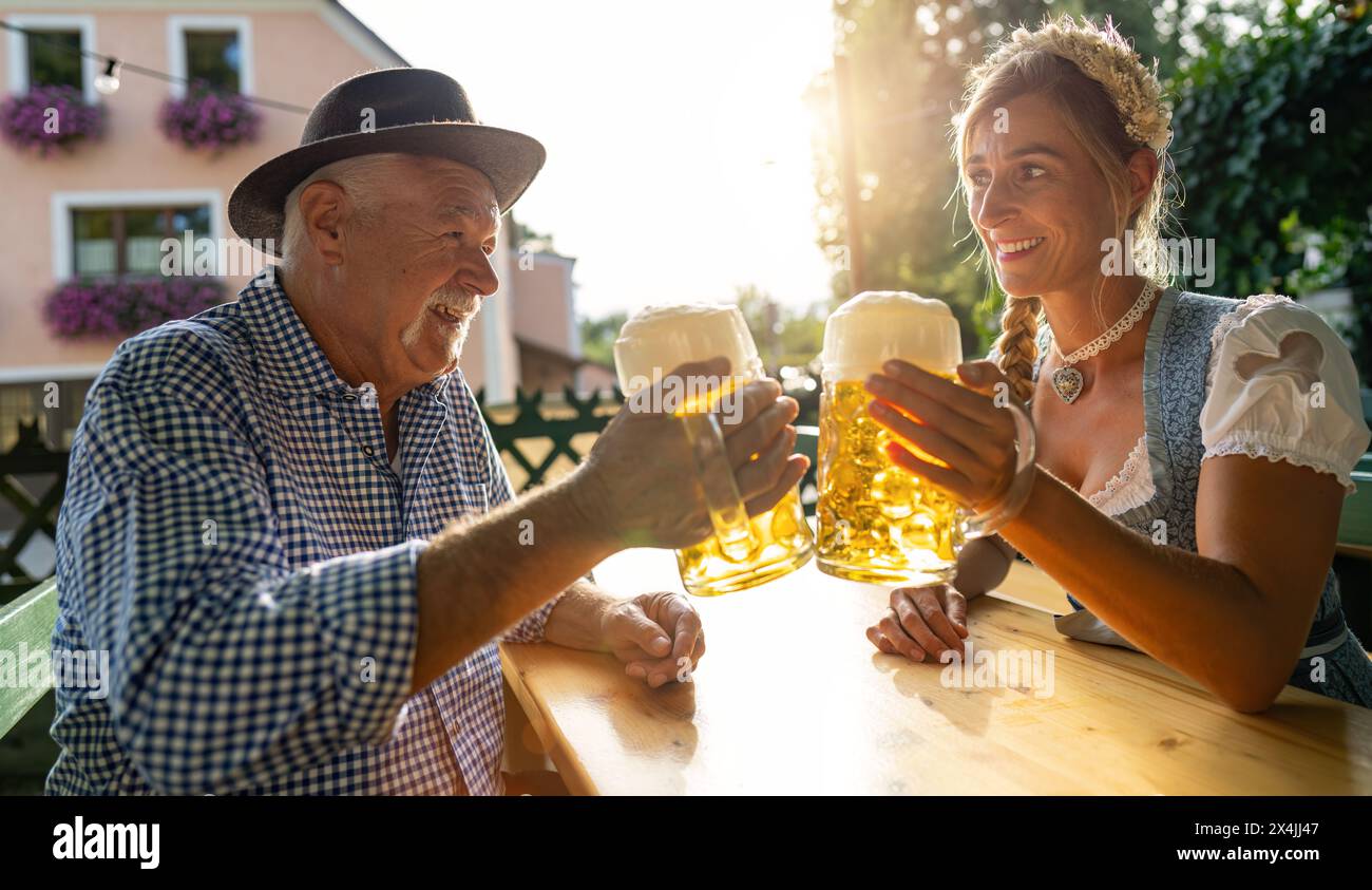 Smiling elderly man and young woman toasting beer mugs, traditional ...