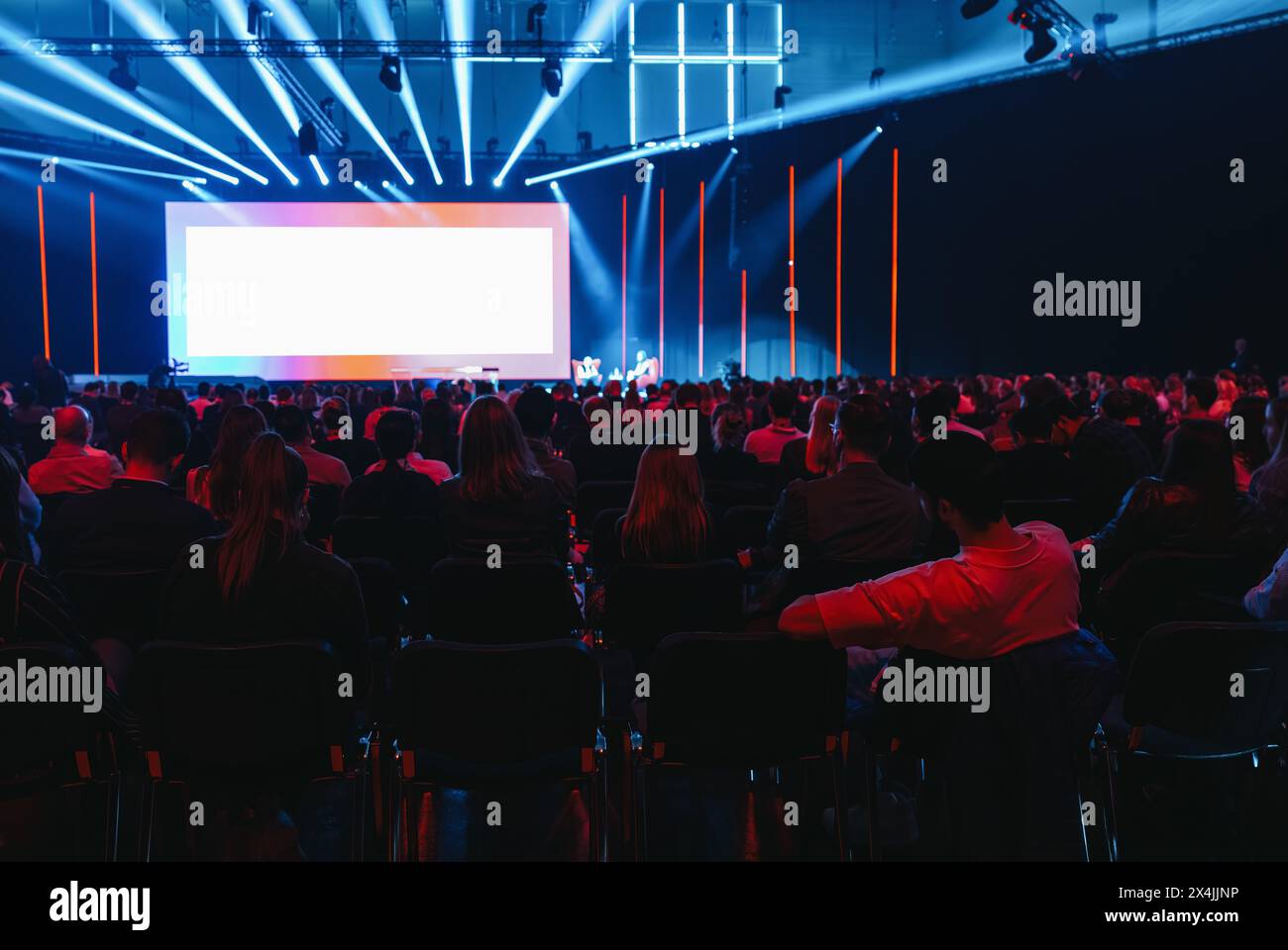 Conference audience facing a bright screen with vivid blue and orange ...