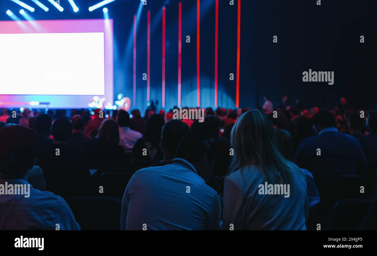 Back view of seated audience in a conference room with a white ...