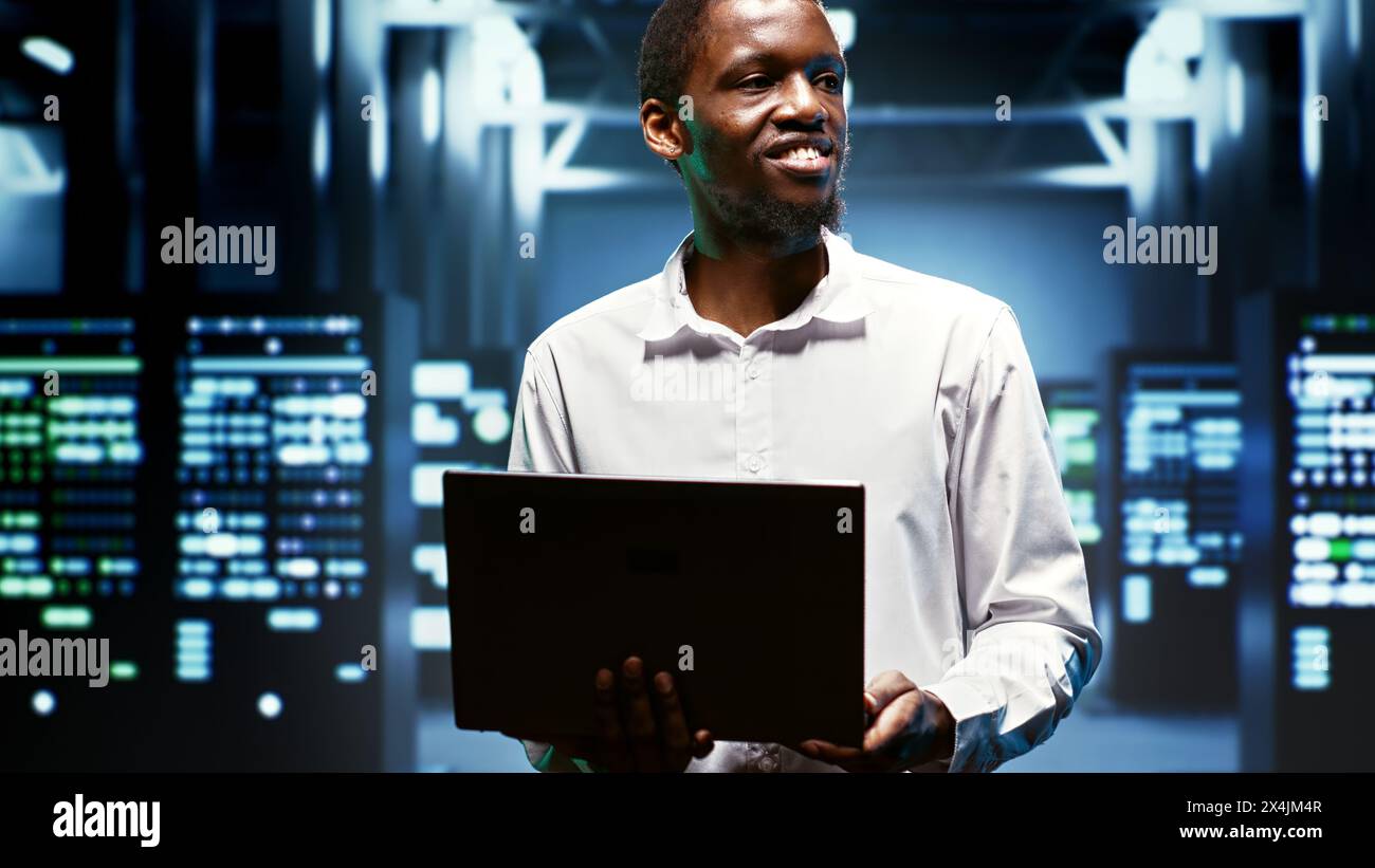 Cheerful system administrator using laptop to survey energy consumption ...