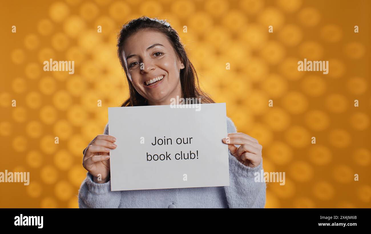 Cheerful book club president holds message urging people to join them ...