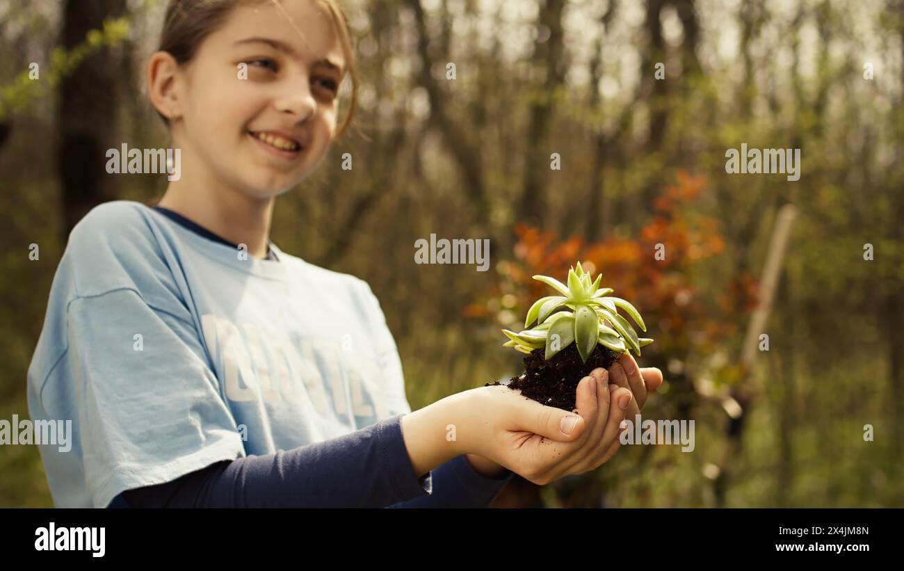 Cute child activist presenting a small seedling tree in her hands ...