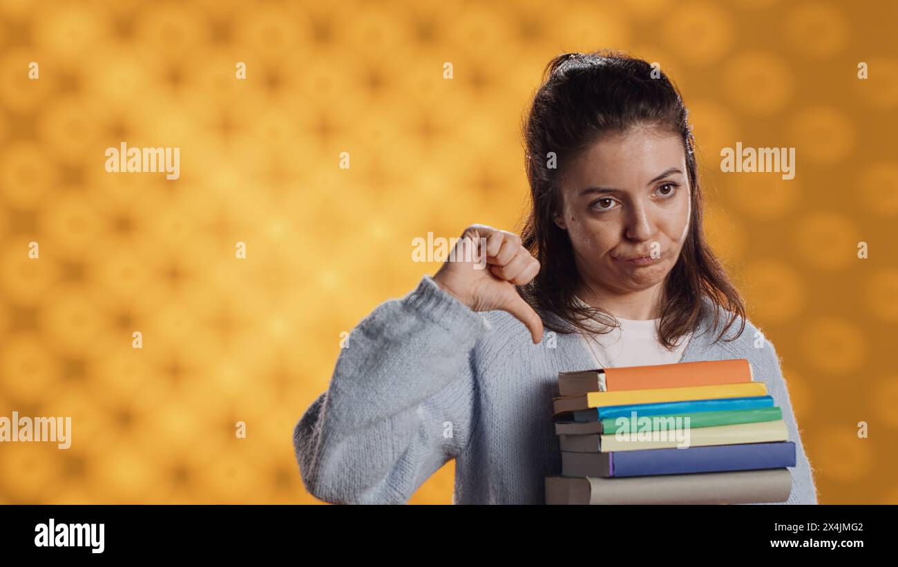 Portrait of woman with pouting expression holding pile of books ...
