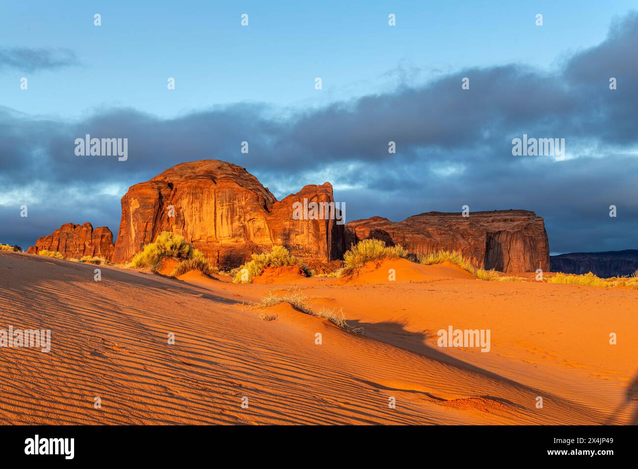 Mountainside lit up by a rising sun casts an orange color against the ...
