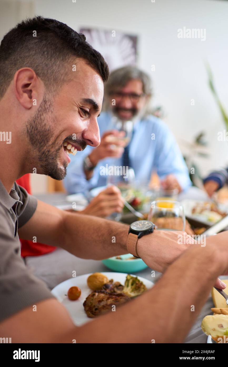 Side view cheerful Caucasian man eating food sitting at table with ...