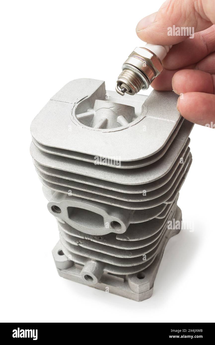 Two-stroke engine cylinder and spark plug in the hand of a master ...