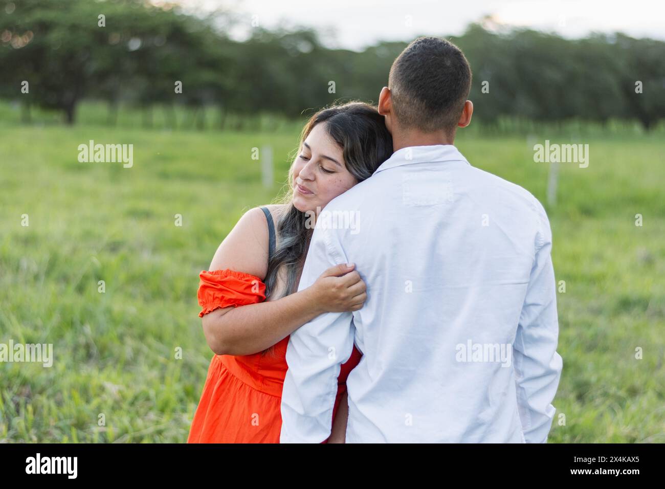 young latina woman hugging her boyfriend while leaning on his shoulder ...