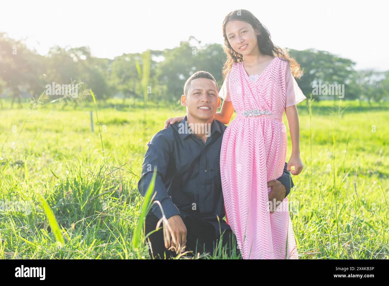 latin father leaning next to his little daughter looking straight ahead ...