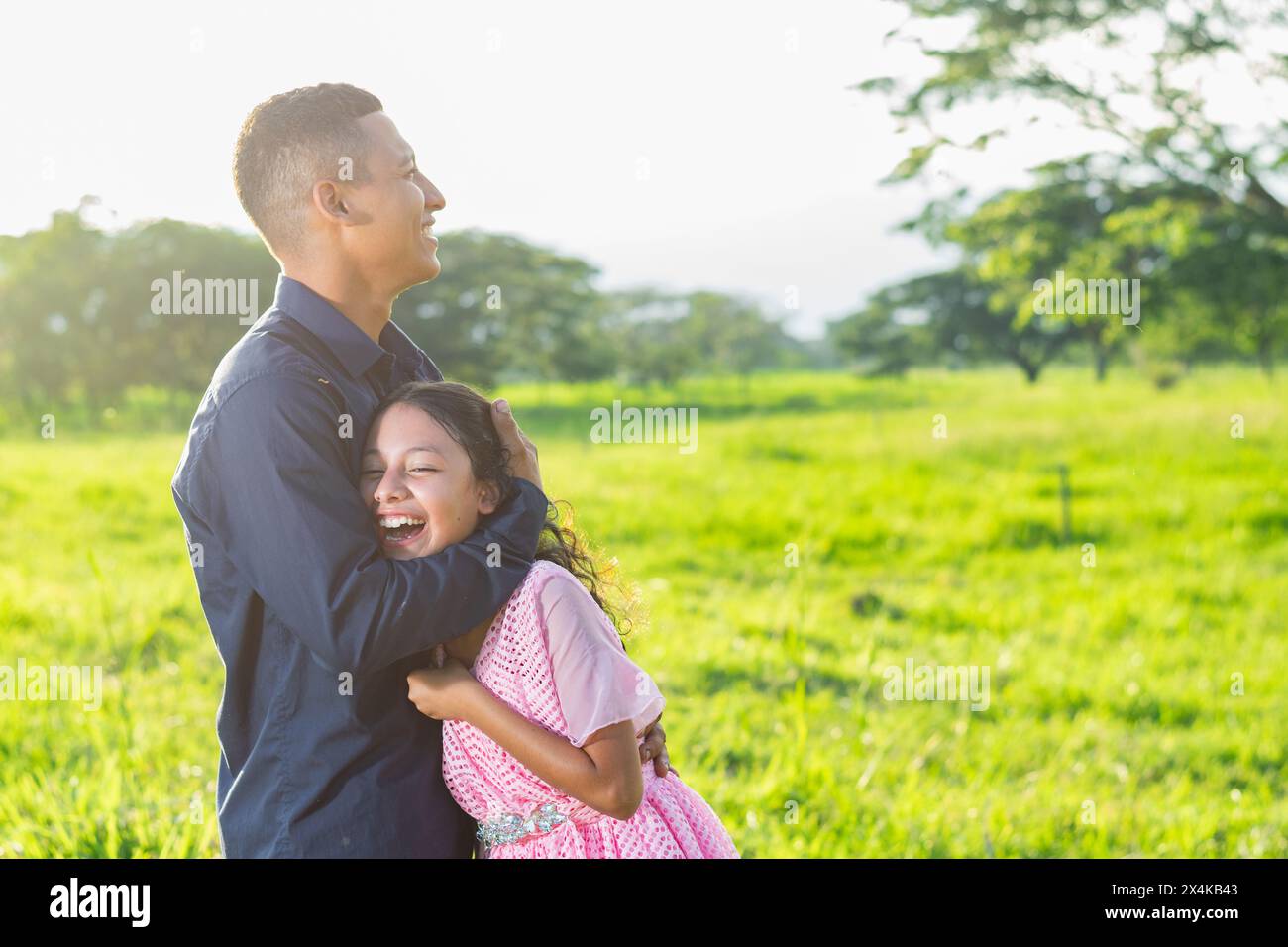 Latin father hugging his little daughter while looking up at the sky ...