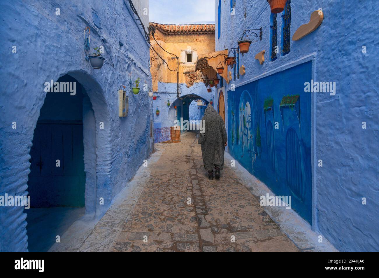 Man walking on narrow street in medina of blue city. Man wearing ...