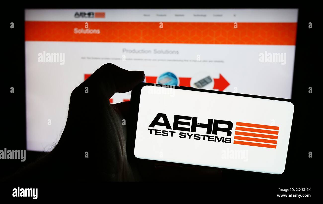 Person holding mobile phone with logo of American semiconductor testing ...