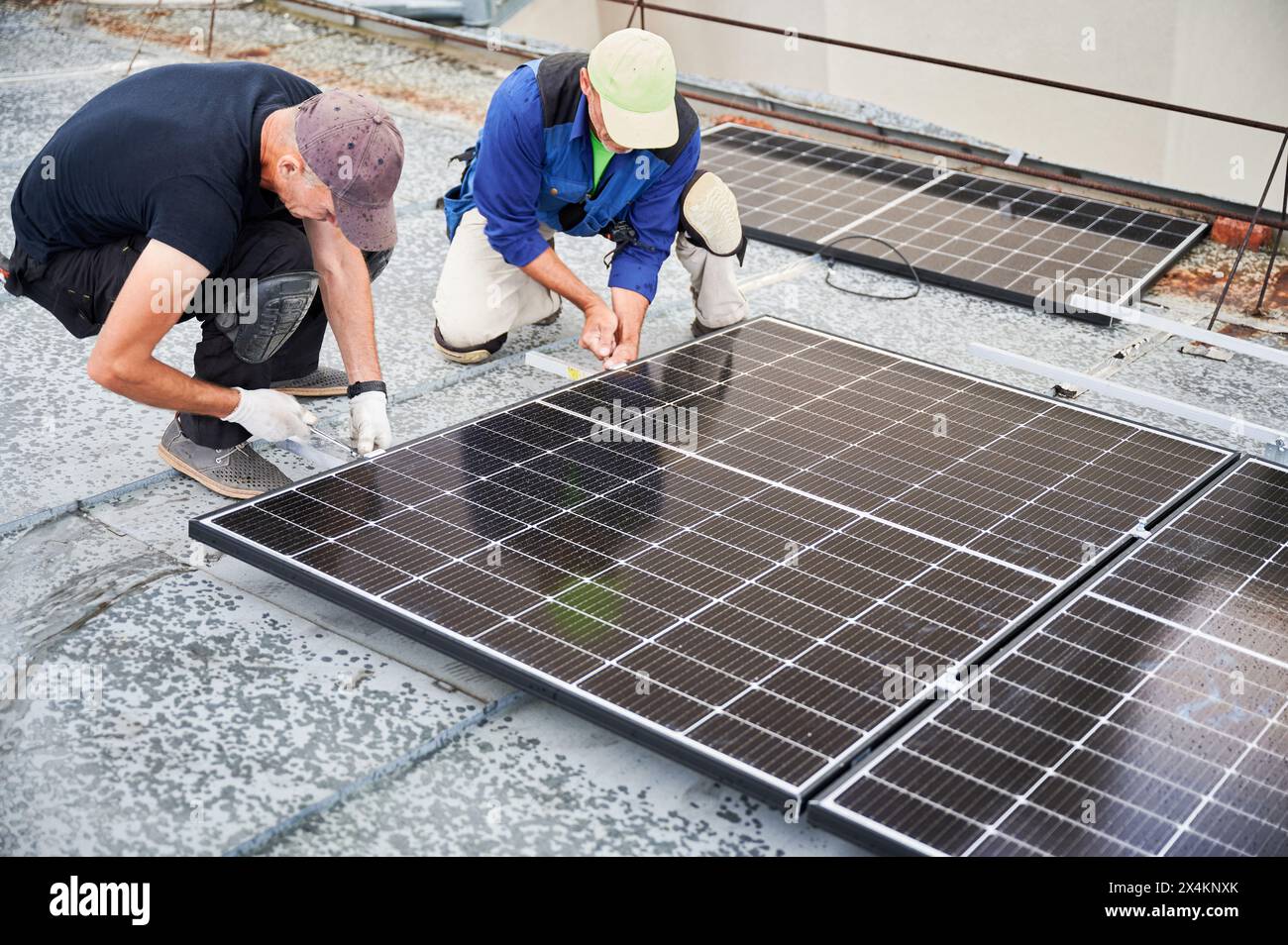 Workers building photovoltaic solar panel system on metal rooftop of ...