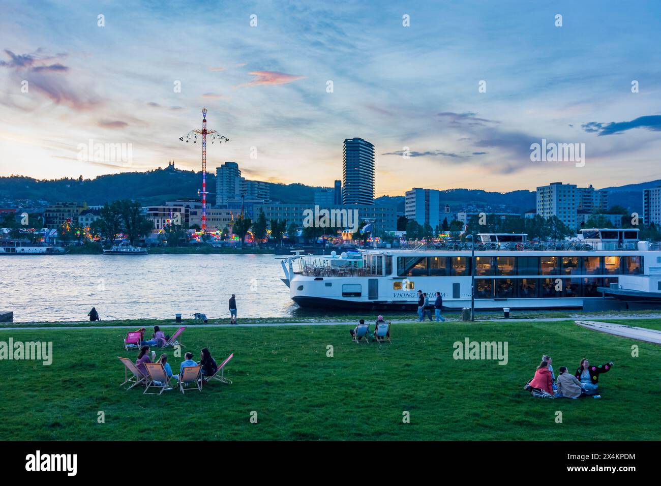 river Donau Danube, cruise ship, people sitting on meadow, festival ...