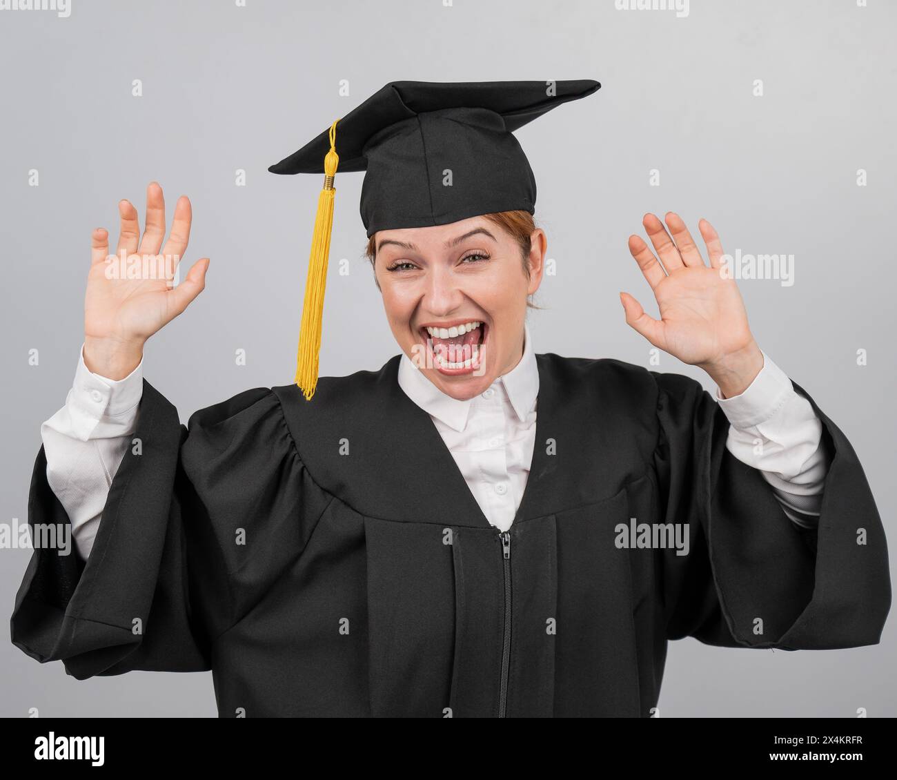 Caucasian woman dancing in graduation gown on white background Stock ...