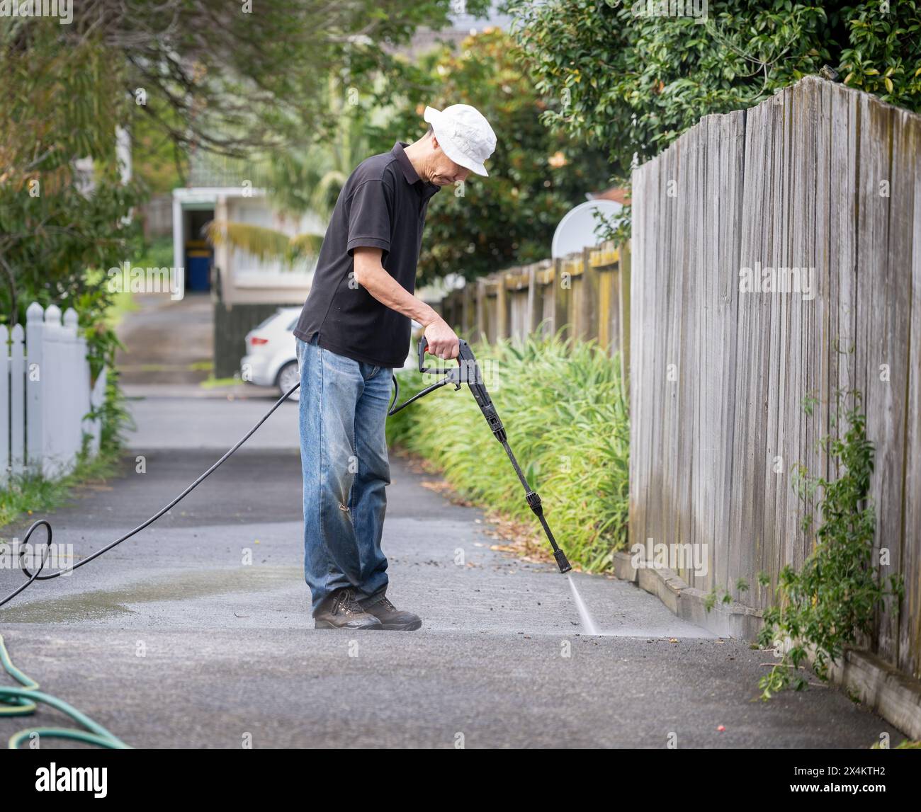 Man cleaning concrete driveway using a water blaster Stock Photo - Alamy