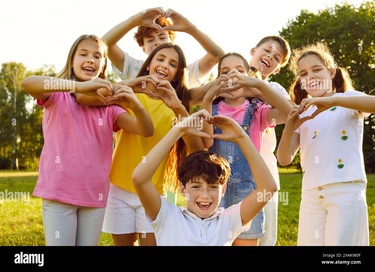 Portrait of a happy smiling children friends making heart sign by hands ...