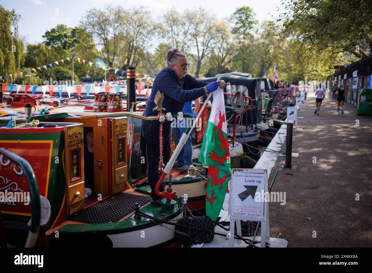 London, UK. 04th May, 2024. A narrowboat owner attaches a Welsh flag to ...
