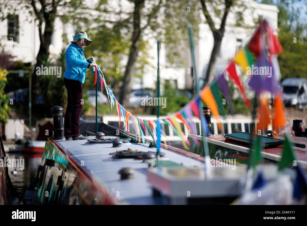 London, UK. 04th May, 2024. A narrowboat owner attaches bunting to her ...
