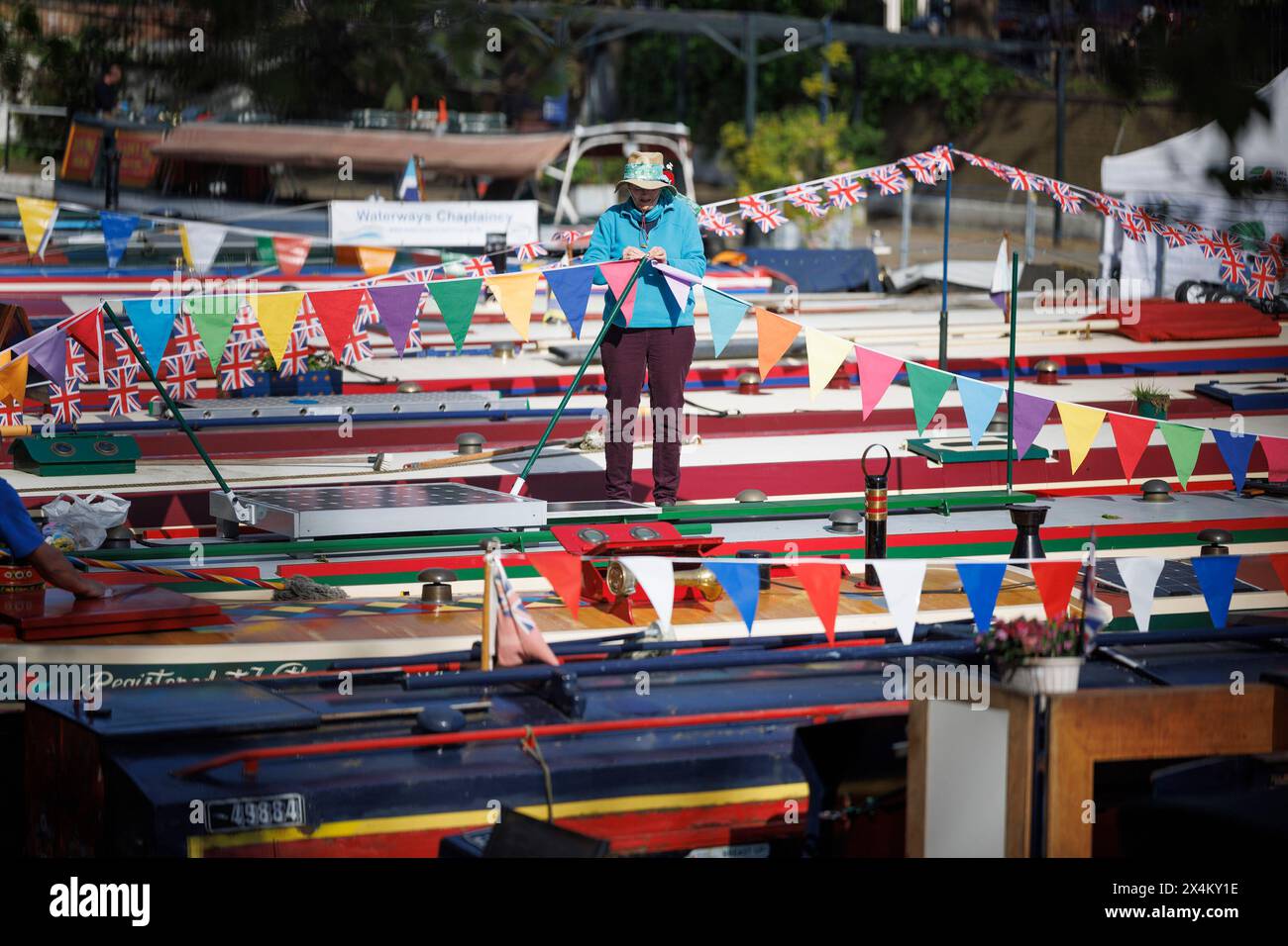 London, UK. 04th May, 2024. A narrowboat owner attaches bunting to her ...