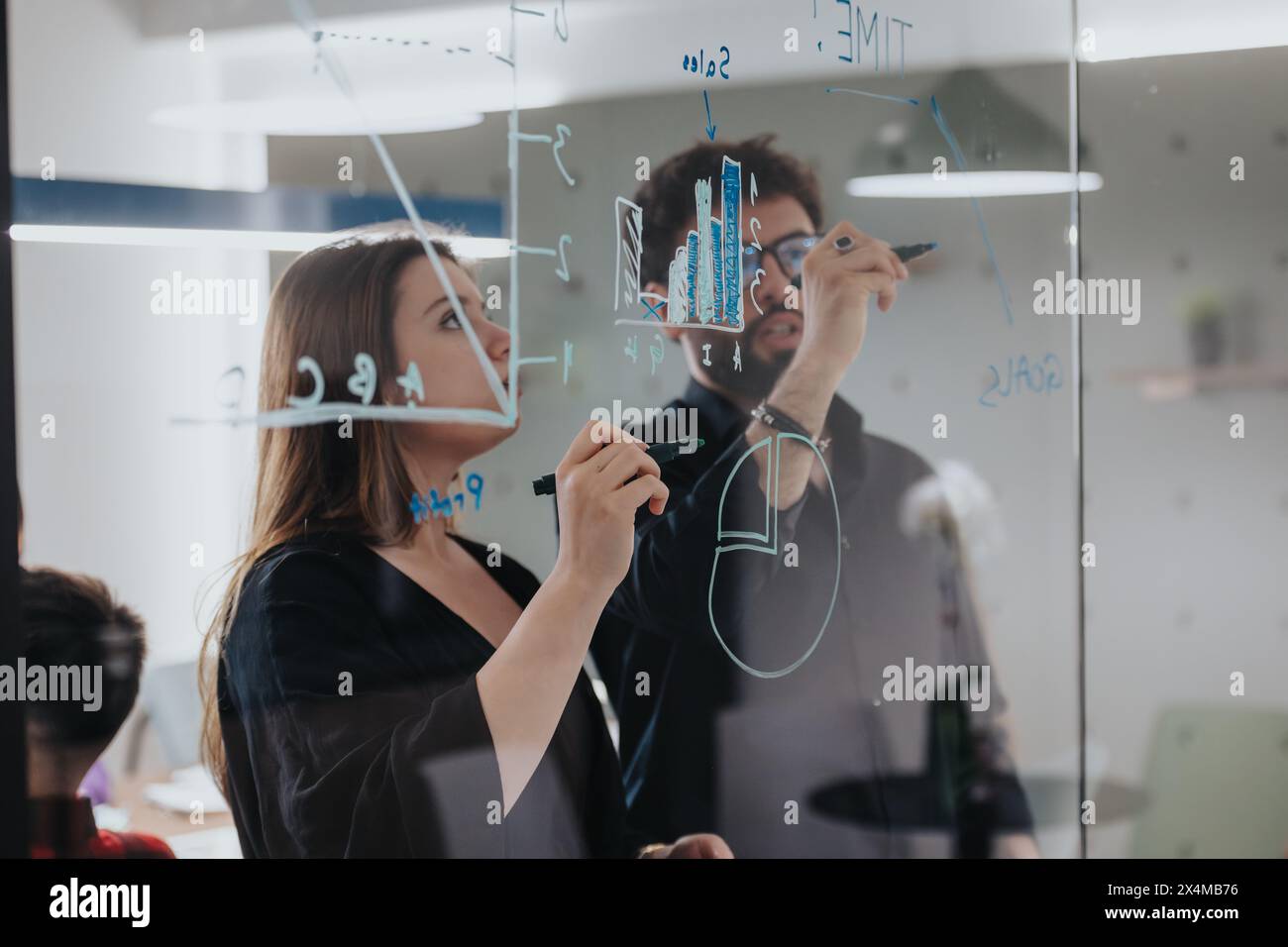 Business professionals brainstorming using sticky notes on a glass wall ...