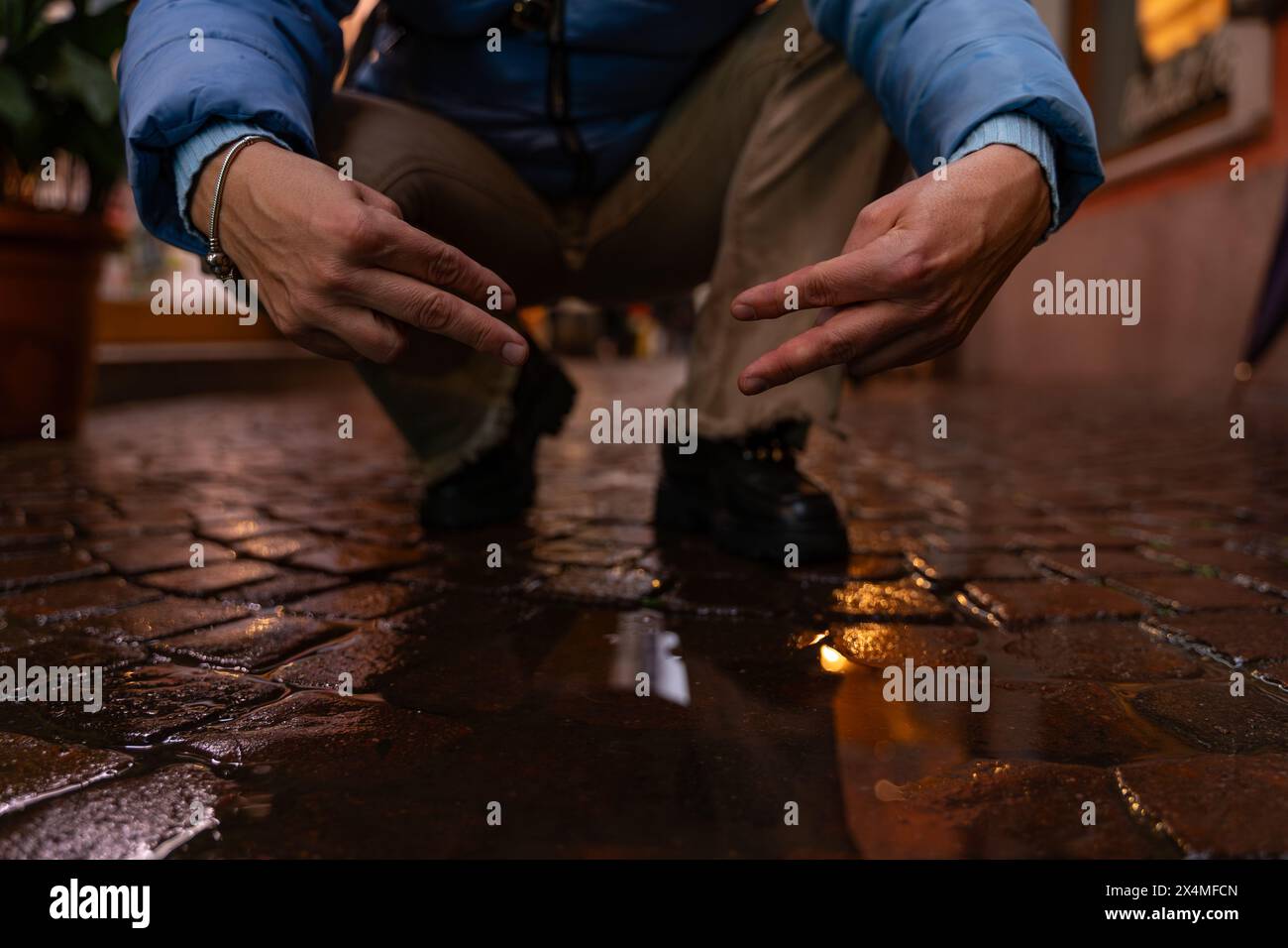 woman in blue sneakers bending over a puddle showing the victory sign ...