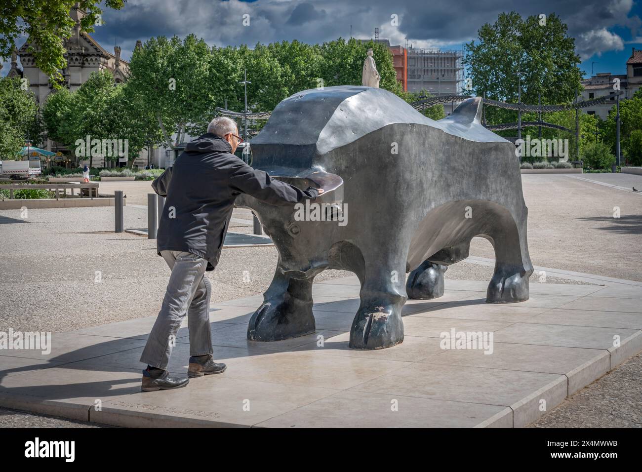 Nîmes, France - 04 17 2024: View of the Bull Nîmes statue and a man ...