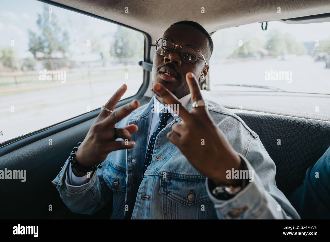 Stylish young businessman flashing peace signs from a car Stock Photo ...