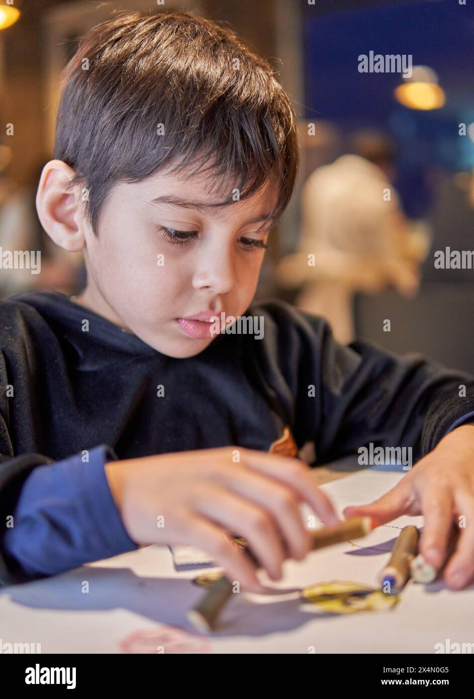 Latino boy in a bar entertaining drawing and painting with a paper and ...