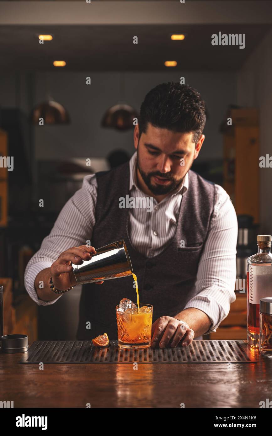 Focused bartender expertly mixes a drink, showcasing his skill in a ...