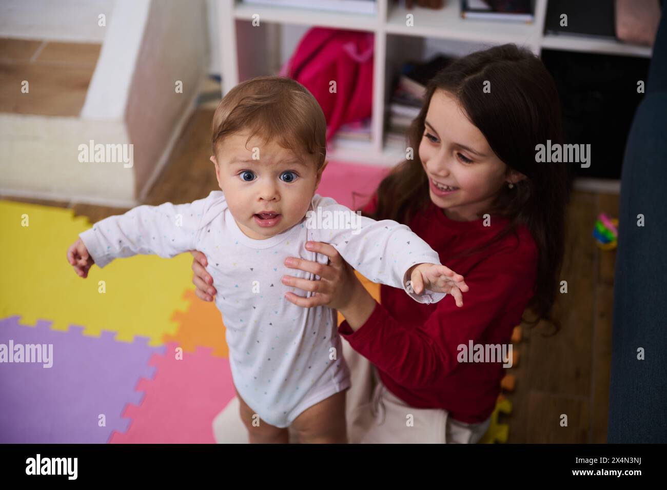 European cute baby boy in the hands of his loving caring sister. Child ...