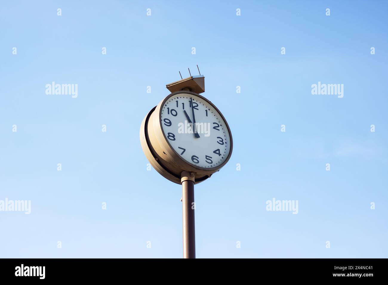 A quartz clock mounted on a metal pole displays the time as 1155 ...