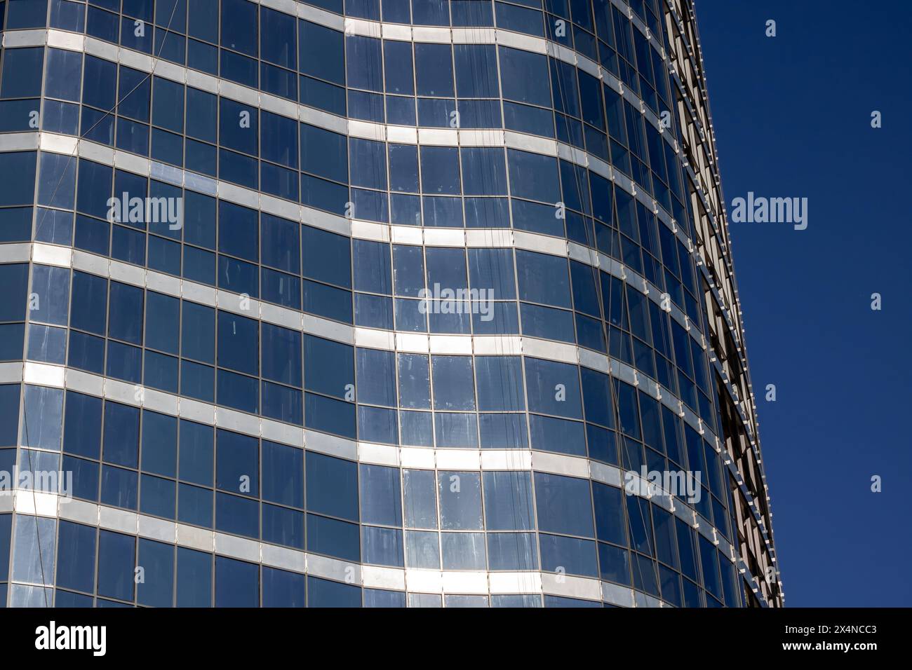 A modern skyscraper with a sleek facade stands tall against the backdrop of a clear blue sky ...