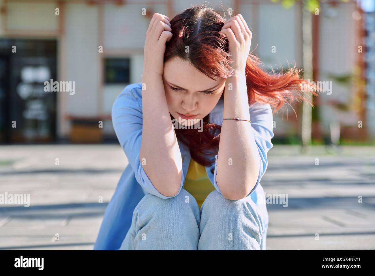 Upset sad unhappy young female sitting outdoor on steps Stock Photo - Alamy