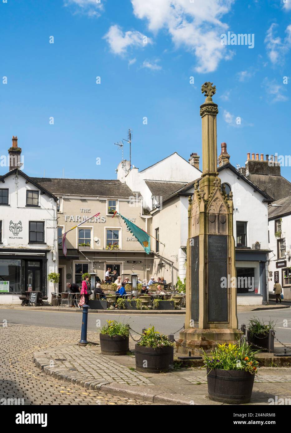 Ulverston war memorial with people sat outside the Farmers Arms pub ...