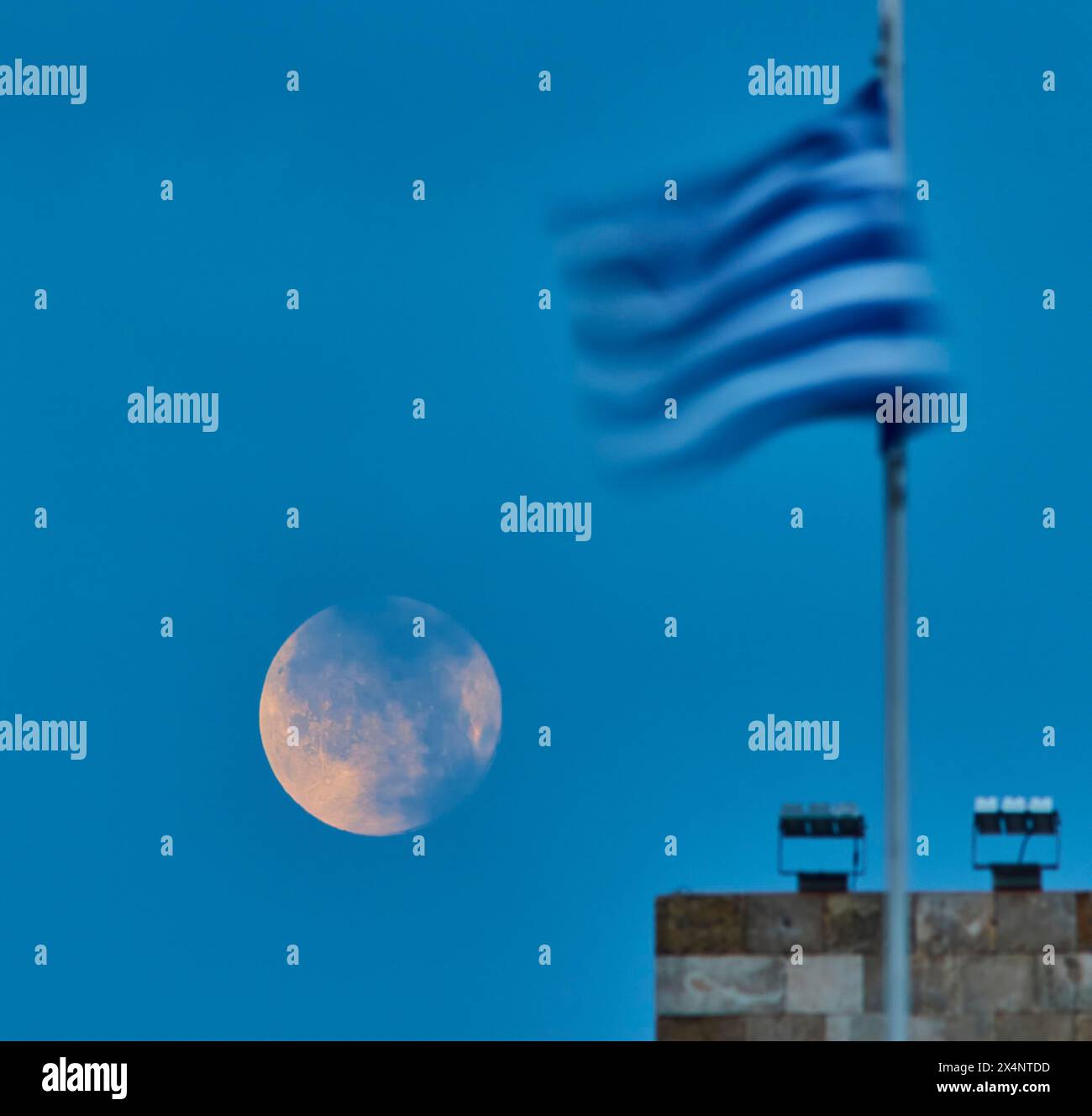 Full moon in semi-darkness next to a blurred flag at dusk, twilight ...
