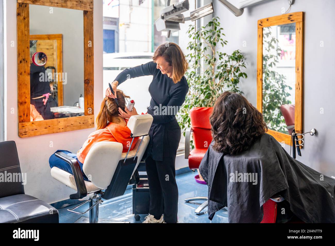 Full length photo of a smiling female hairdresser talking with woman ...