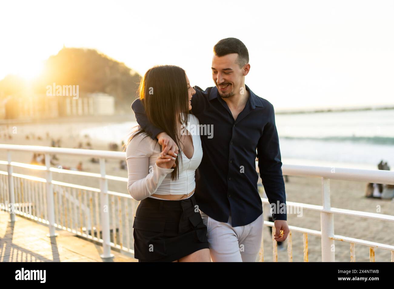 Romantic couple embracing looking at each other walking along a ...