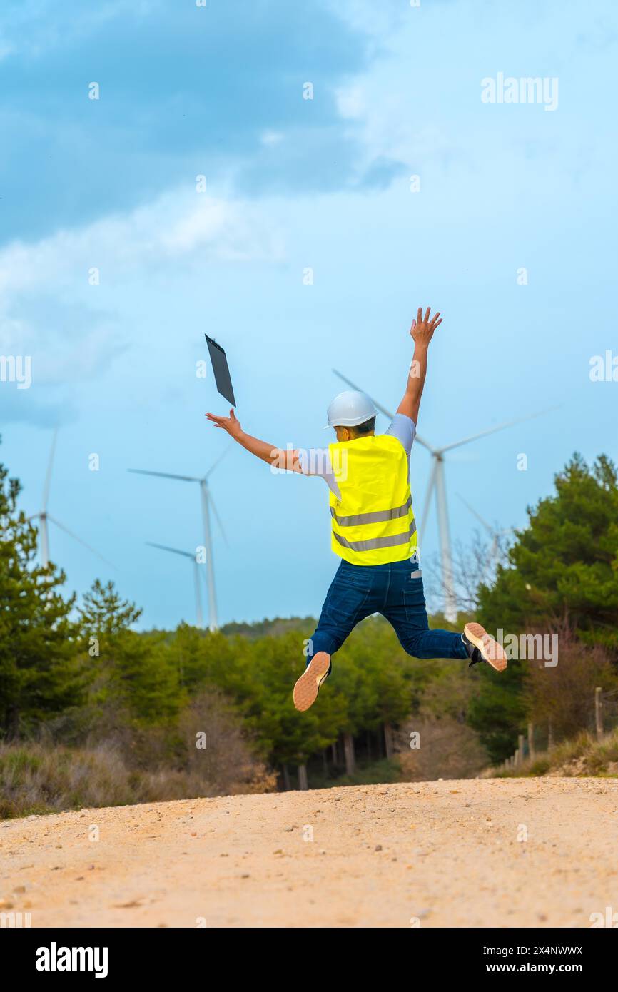 Worker jumping and raising arms in a path in a green energy park Stock ...