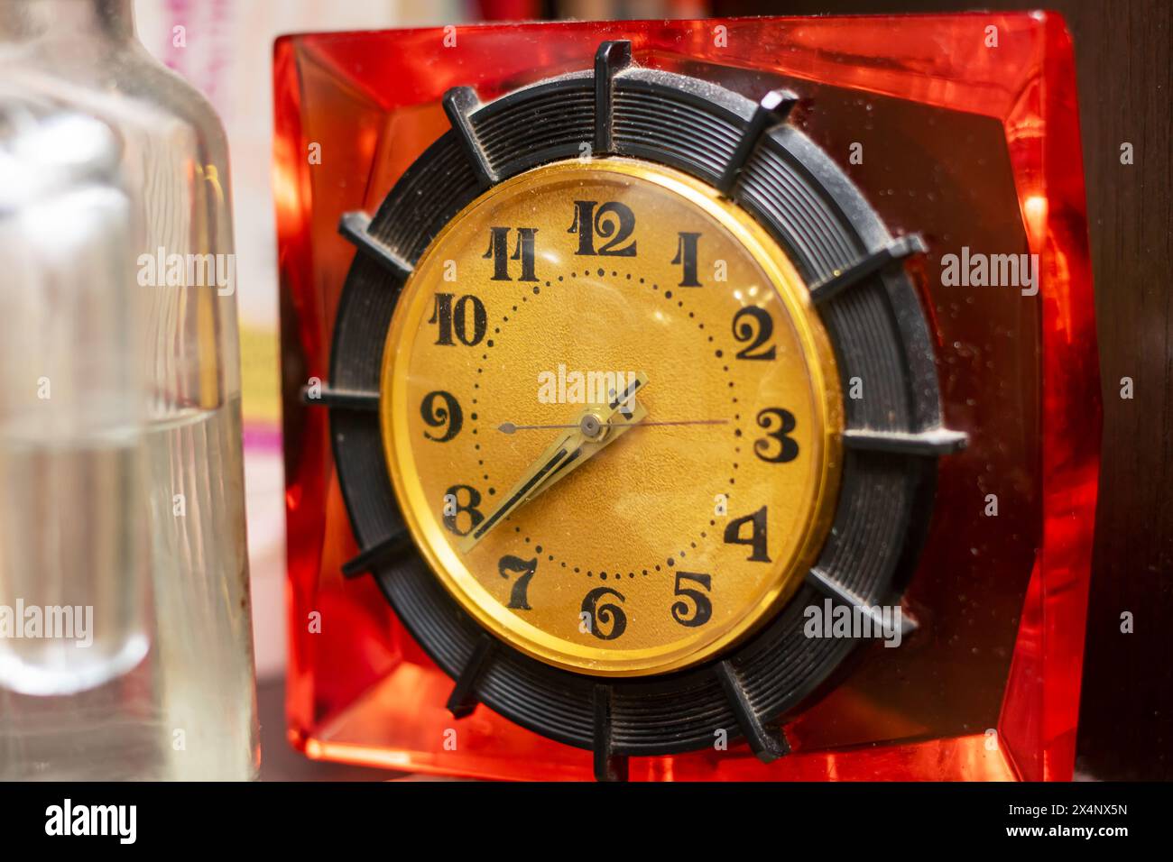 An analog quartz clock in red and black with wooden accents displays ...