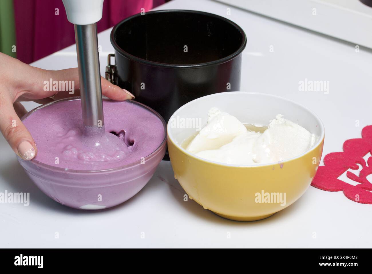 Blueberry cheesecake. A woman mixes blender blueberry jam into cottage ...