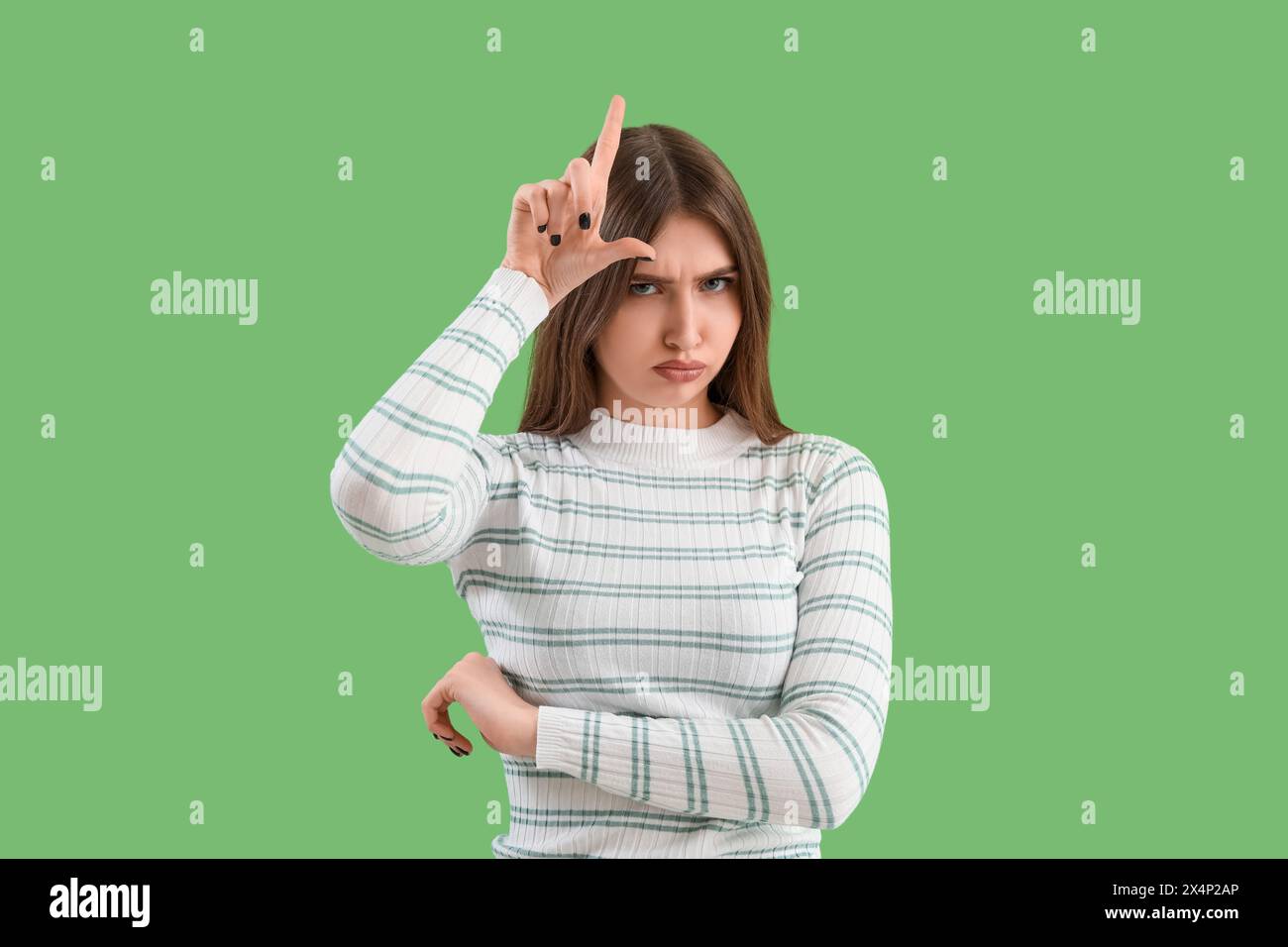 Sad young woman showing loser gesture on green background Stock Photo ...