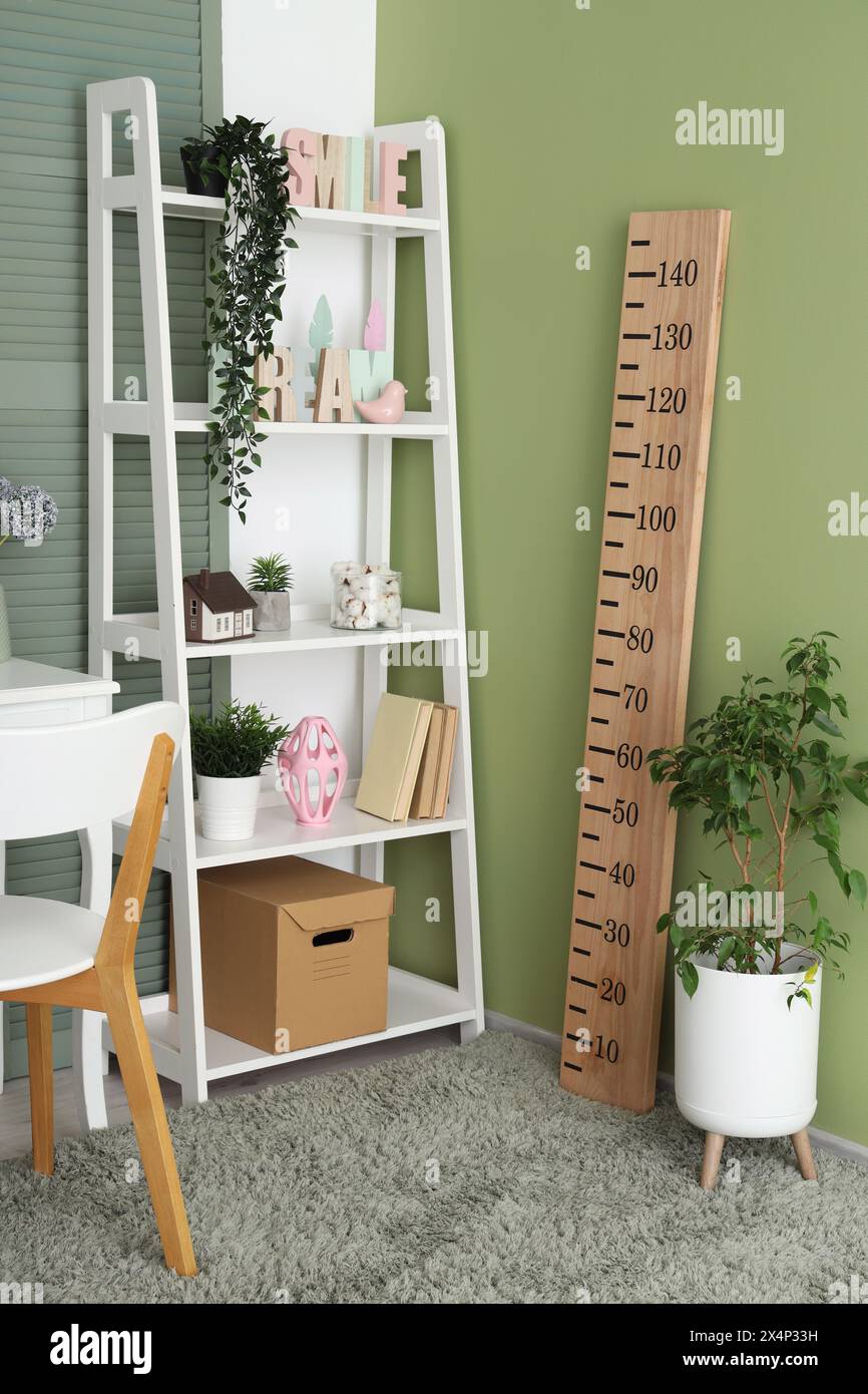 Interior of modern children's room with wooden stadiometer and shelving ...