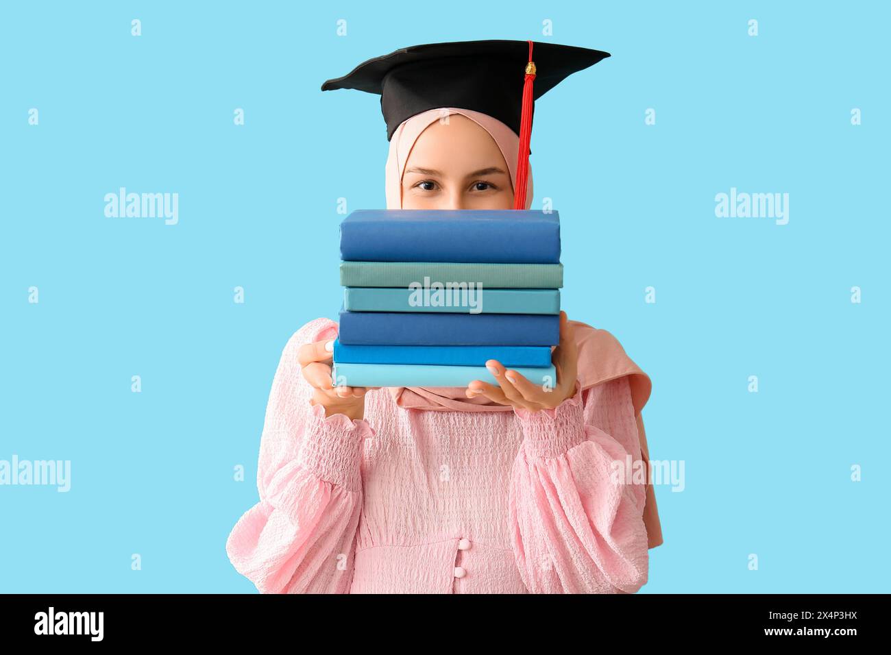Female Muslim graduate with books on blue background Stock Photo - Alamy