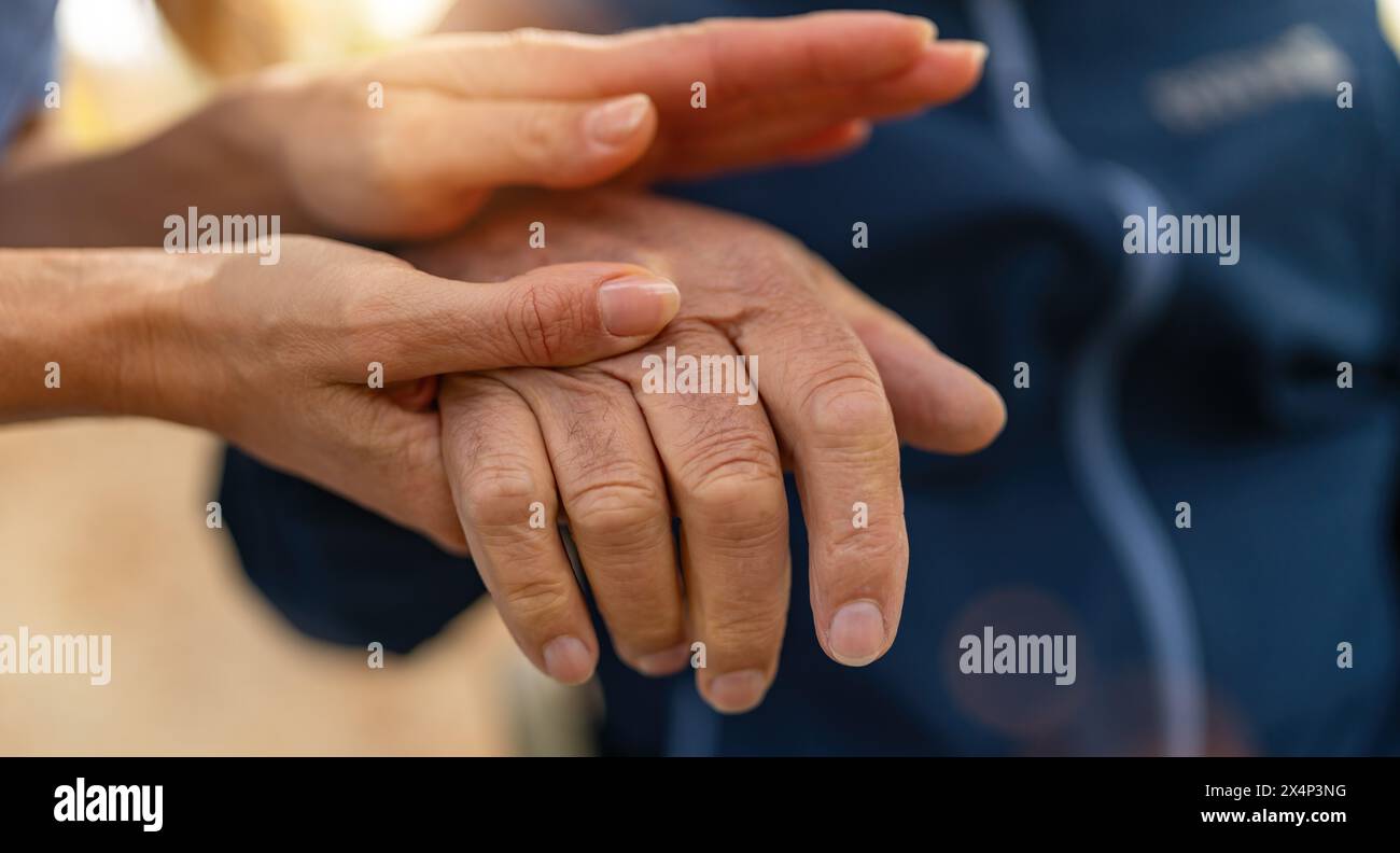 Nurse consoling senior hand of an elderly man in wheelchair, offering ...