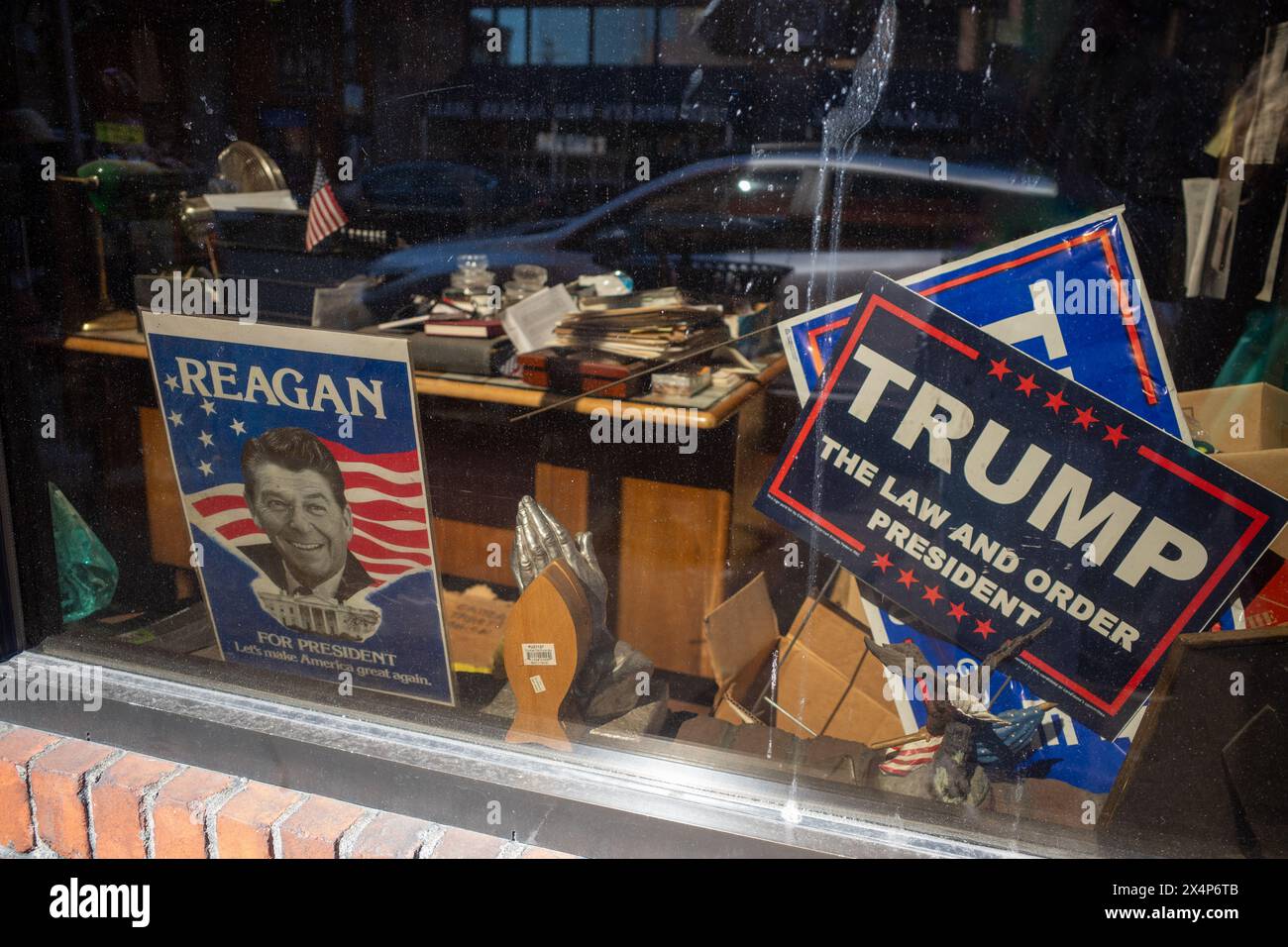 Campaign signs featuring Trump and Reagan peek through a grimy window ...