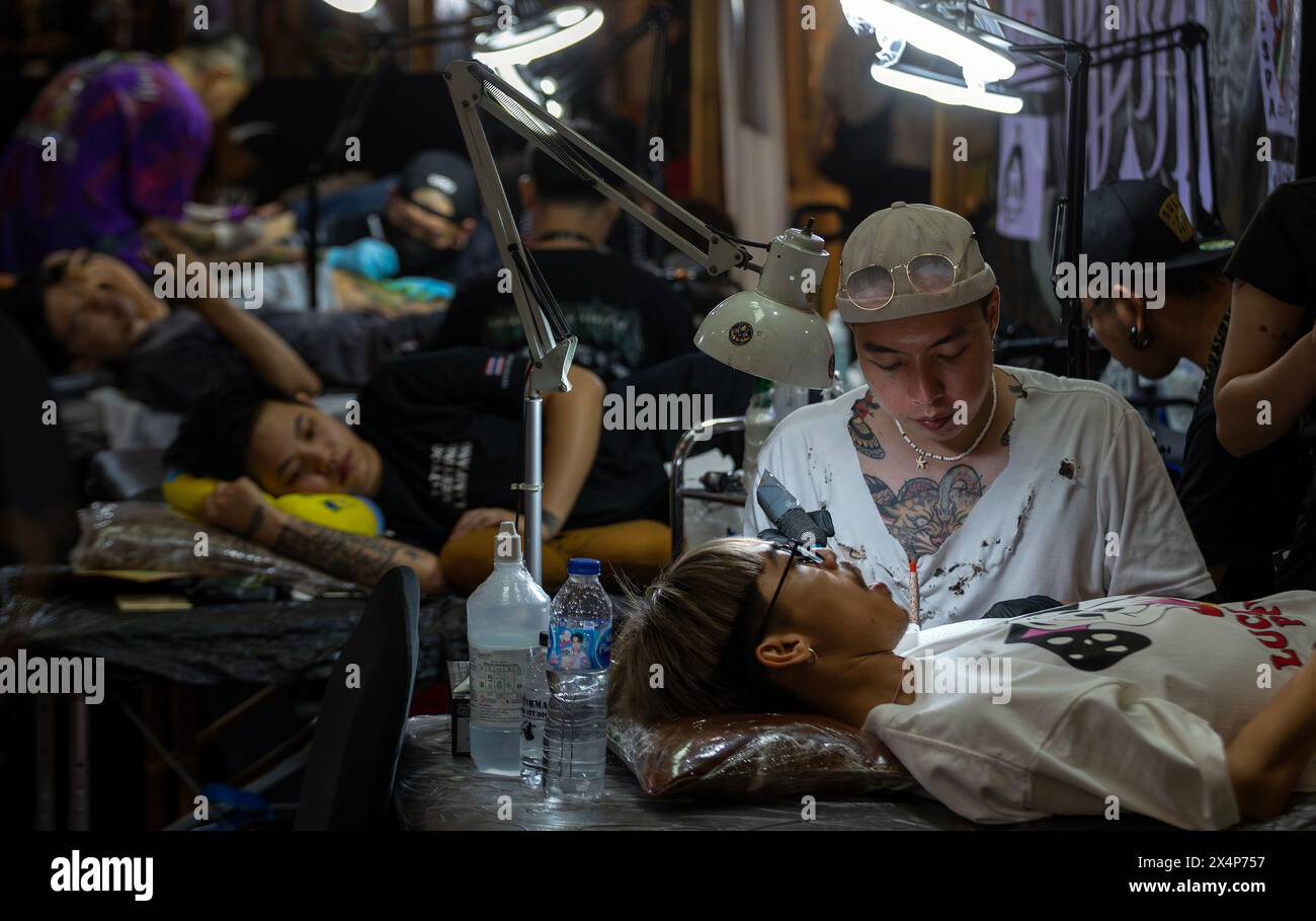 Chiang Mai, Thailand. 4th May, 2024. An artist tattoos a customer ...