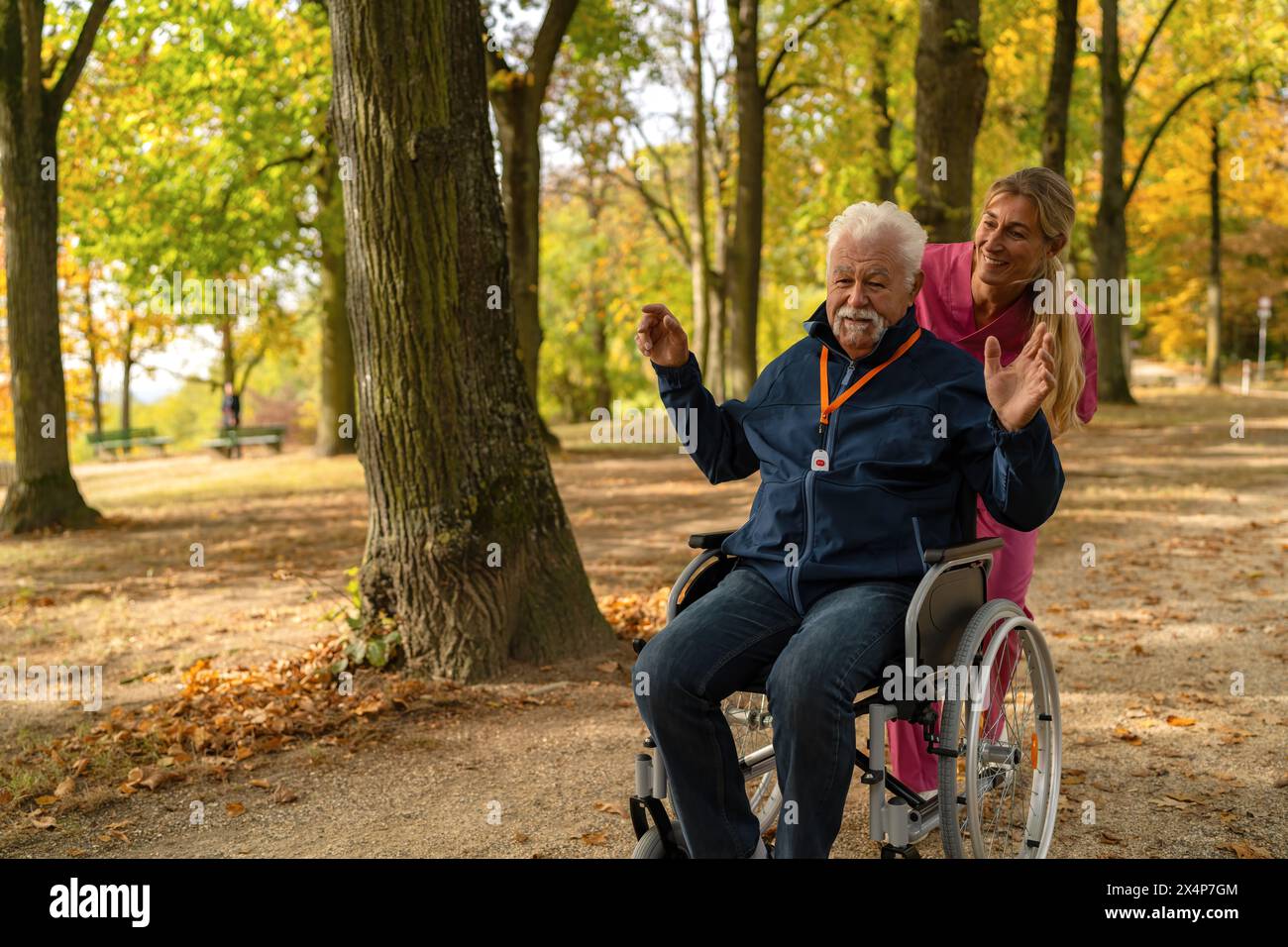 grandfather in wheelchair with nurse in park, autumn setting, wearing a ...