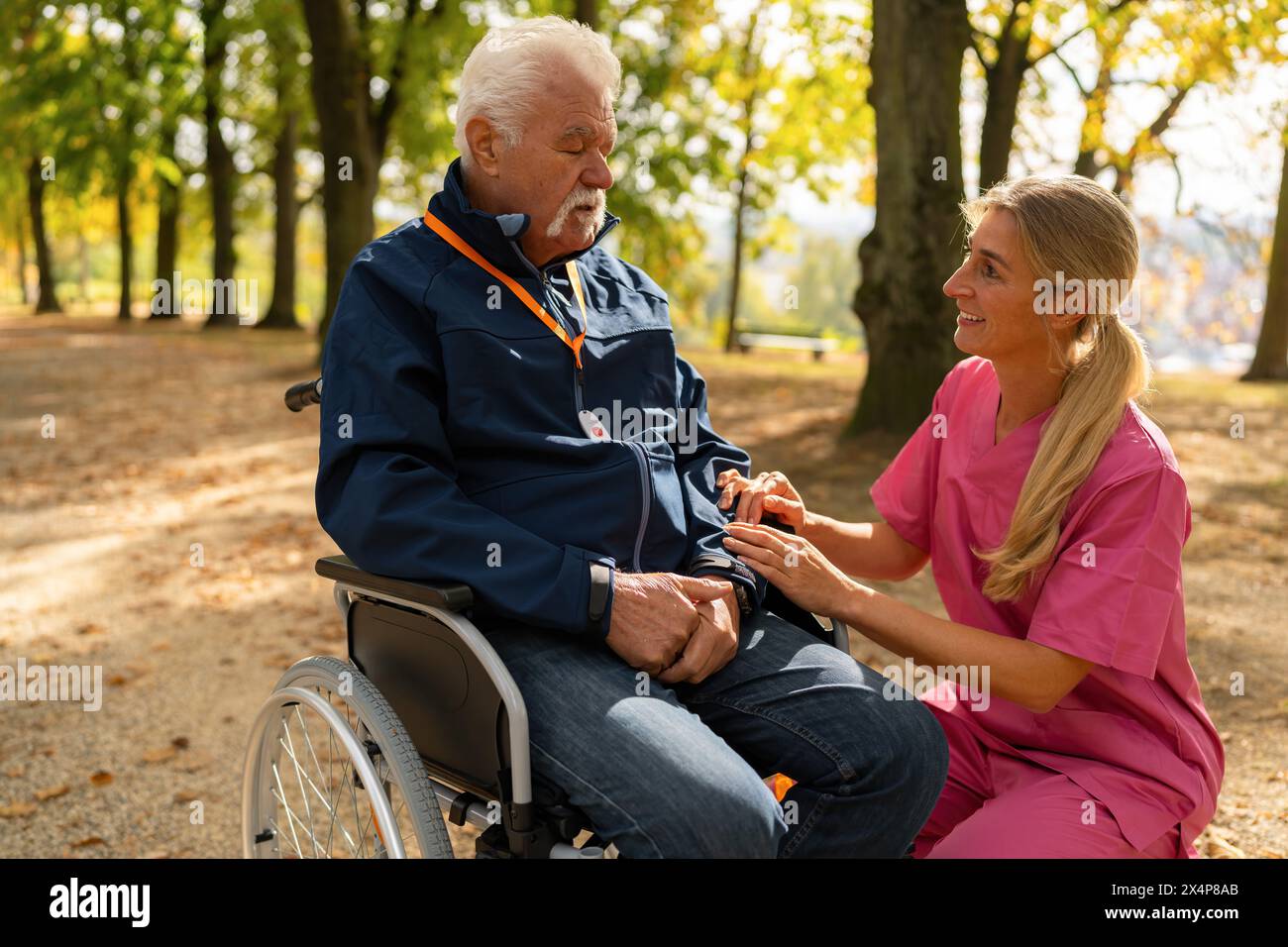 grandpa in wheelchair interacting with caregiver in a park, both ...